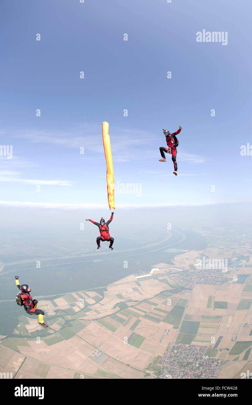 A crazy freefly skydiving team is playing with an air-tube in freefall ...