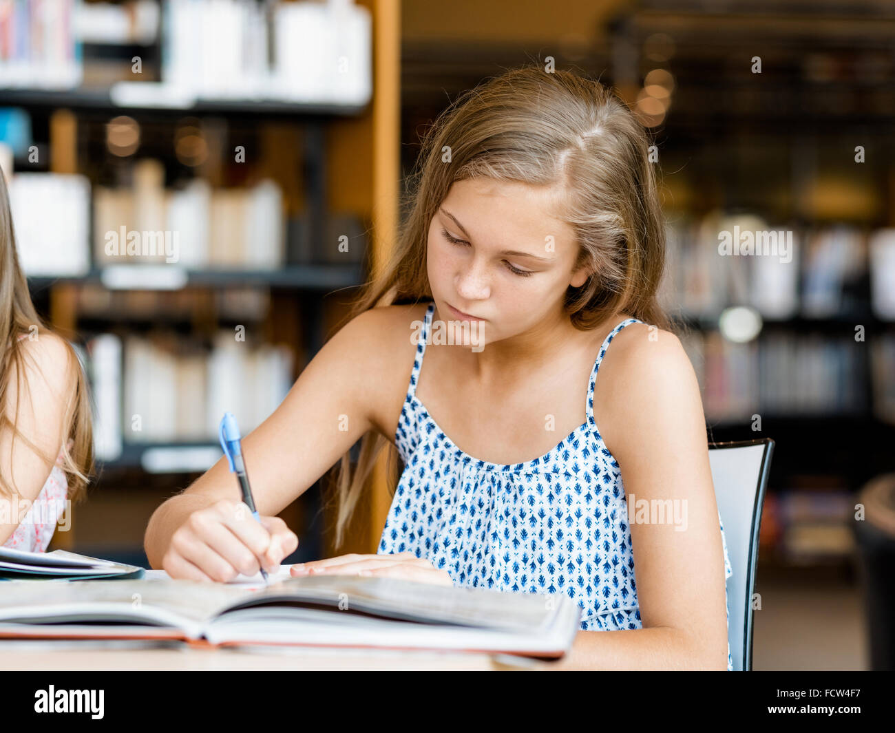Girl doing her homework in library Stock Photo - Alamy