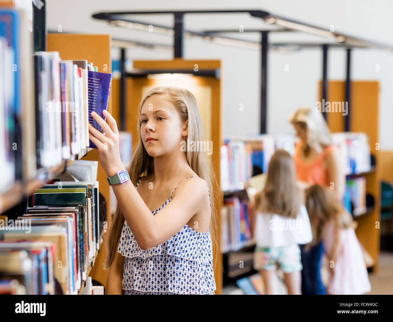 Teenage girl picking a book in public library Stock Photo - Alamy