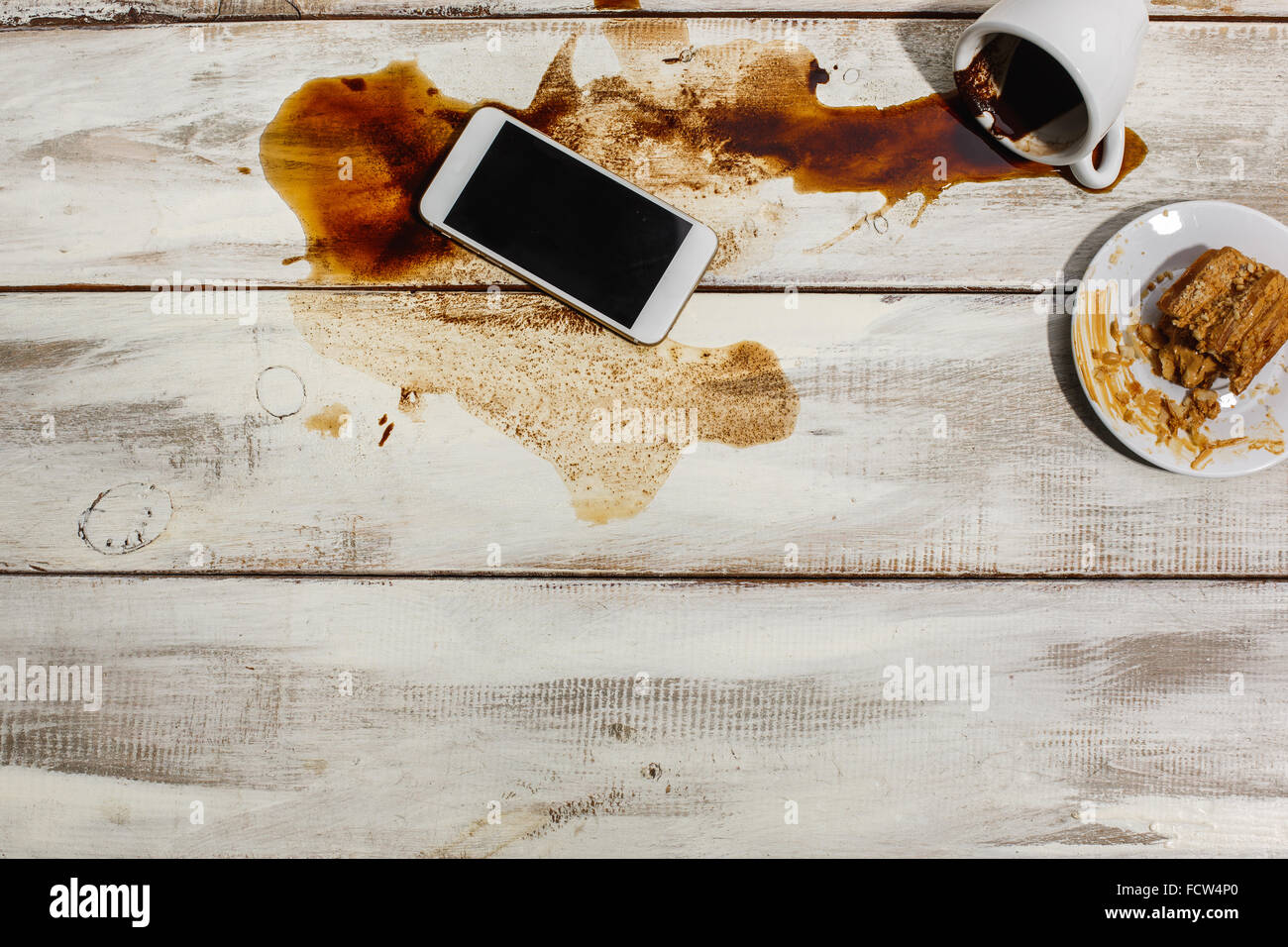 Cup of coffee spilled on wooden table with the phone and and the ...