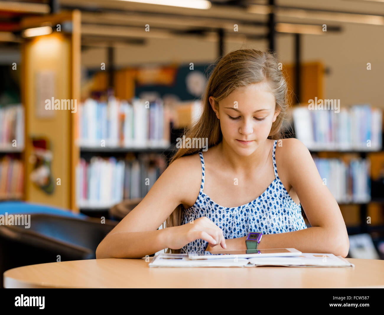 A teenage girl with a book in library Stock Photo - Alamy