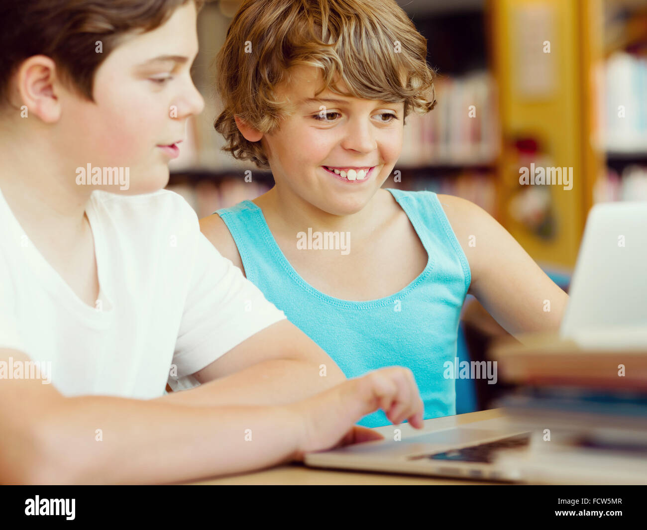 Two boys in library with notebook Stock Photo - Alamy
