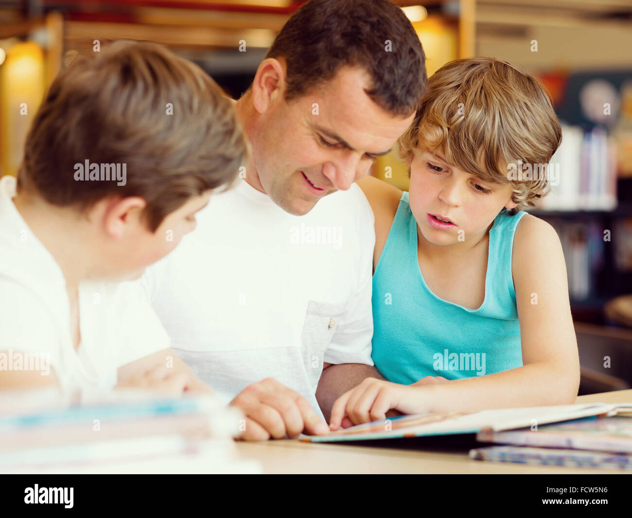 Father with sons in library with books Stock Photo - Alamy