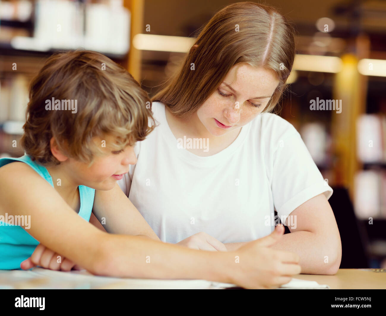 Teenage girl and her brother with books studying in library Stock Photo ...