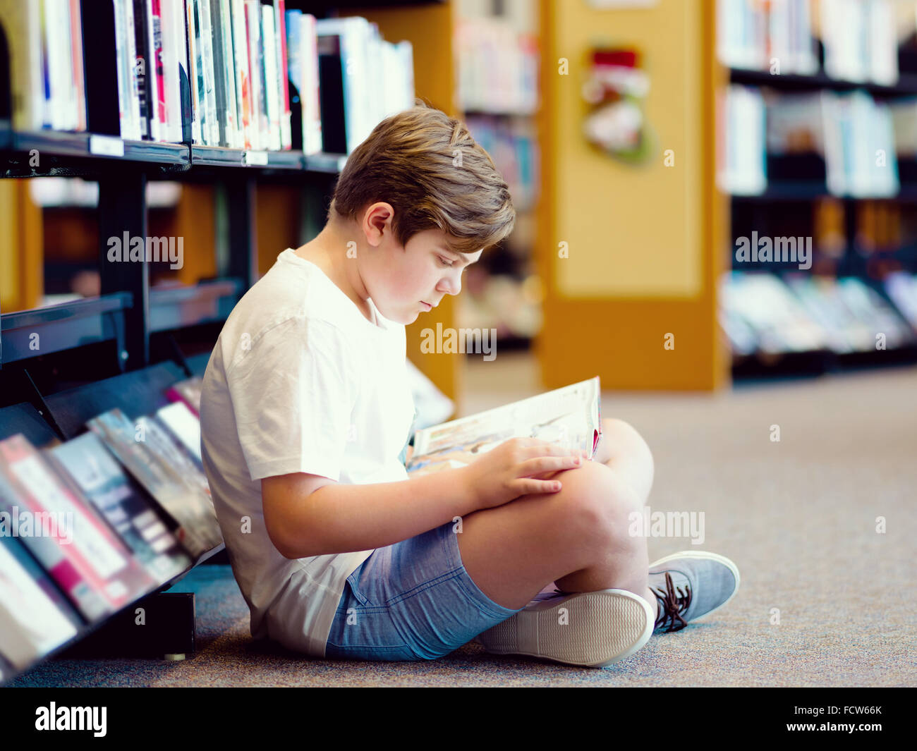 Boy in library with books Stock Photo - Alamy