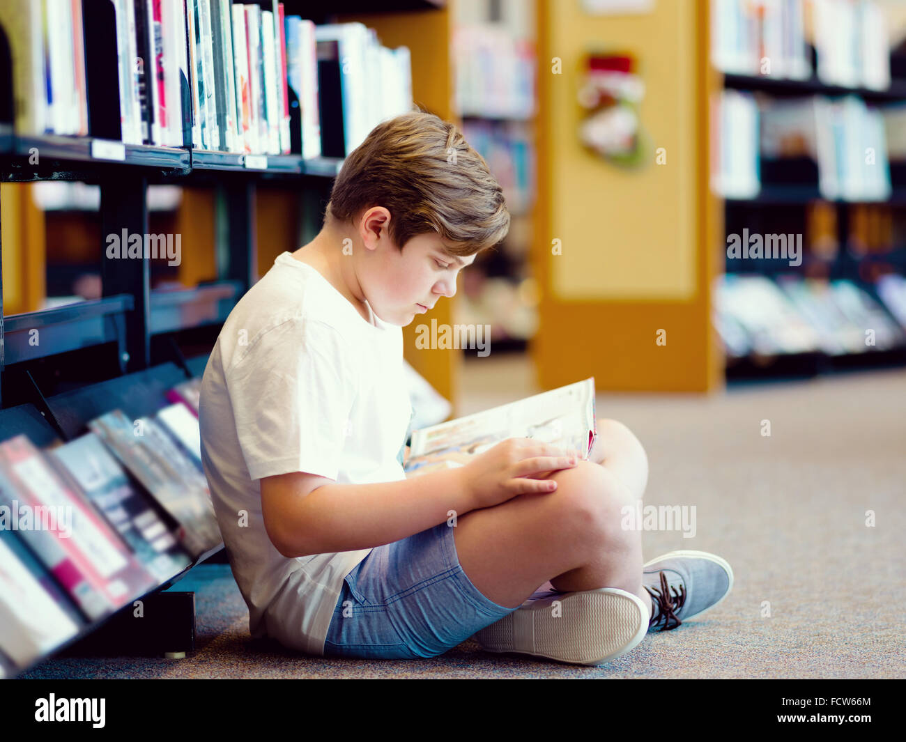 Boy in library with books Stock Photo - Alamy