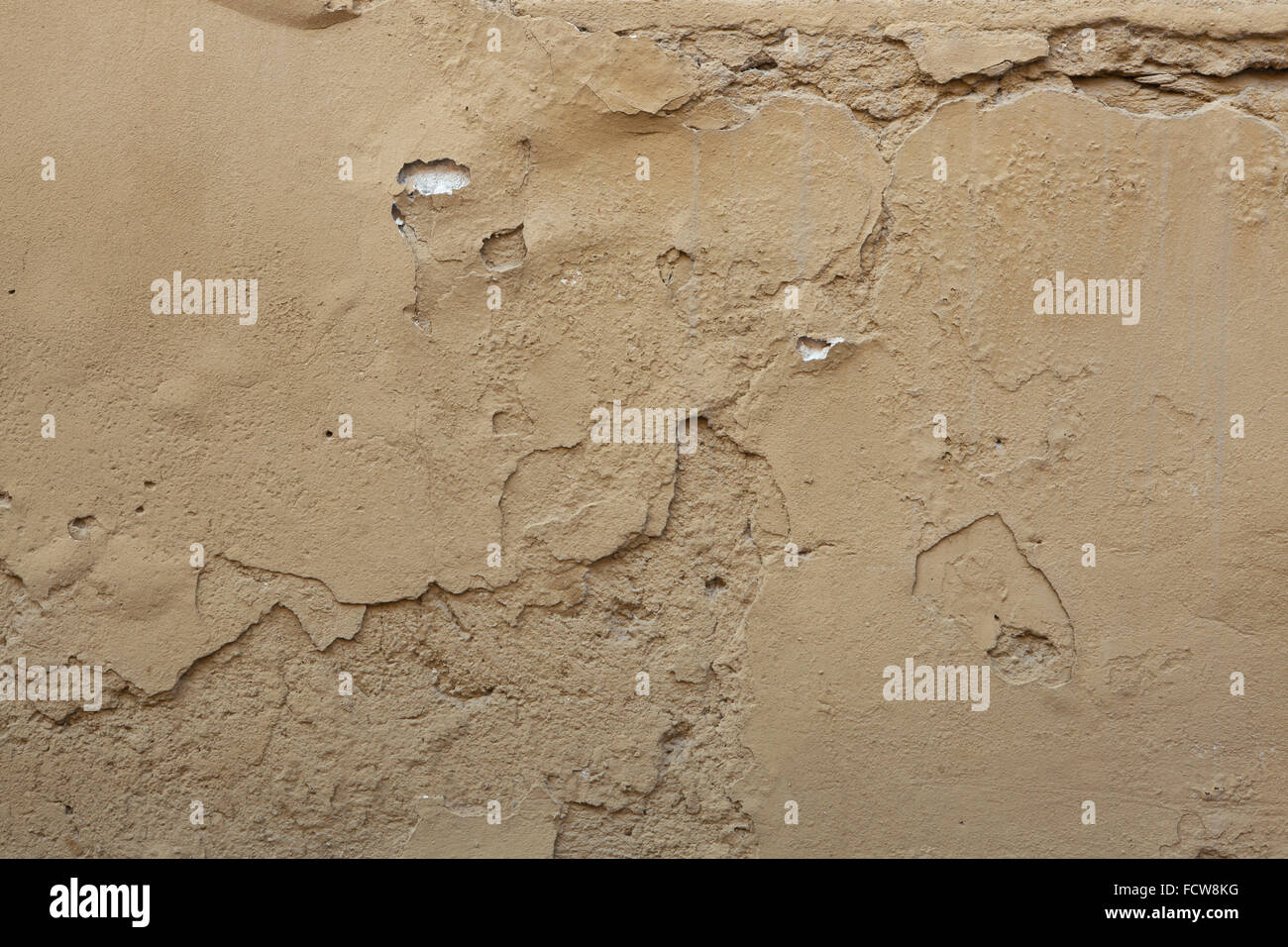 Old ochre painted stucco wall with cracked plaster. Background texture ...