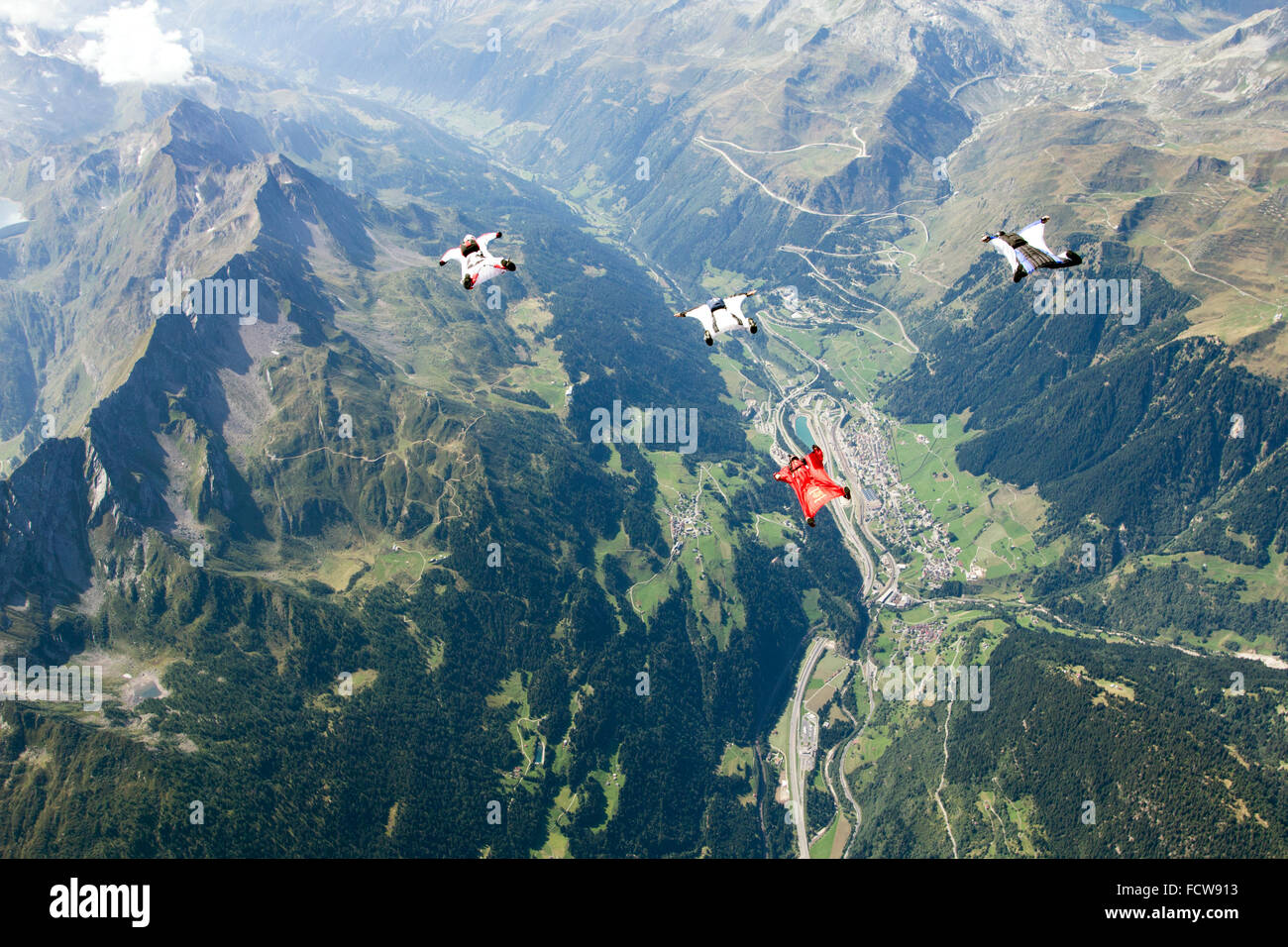 Wingsuit pilots are flying in a group together. The leader in the white ...