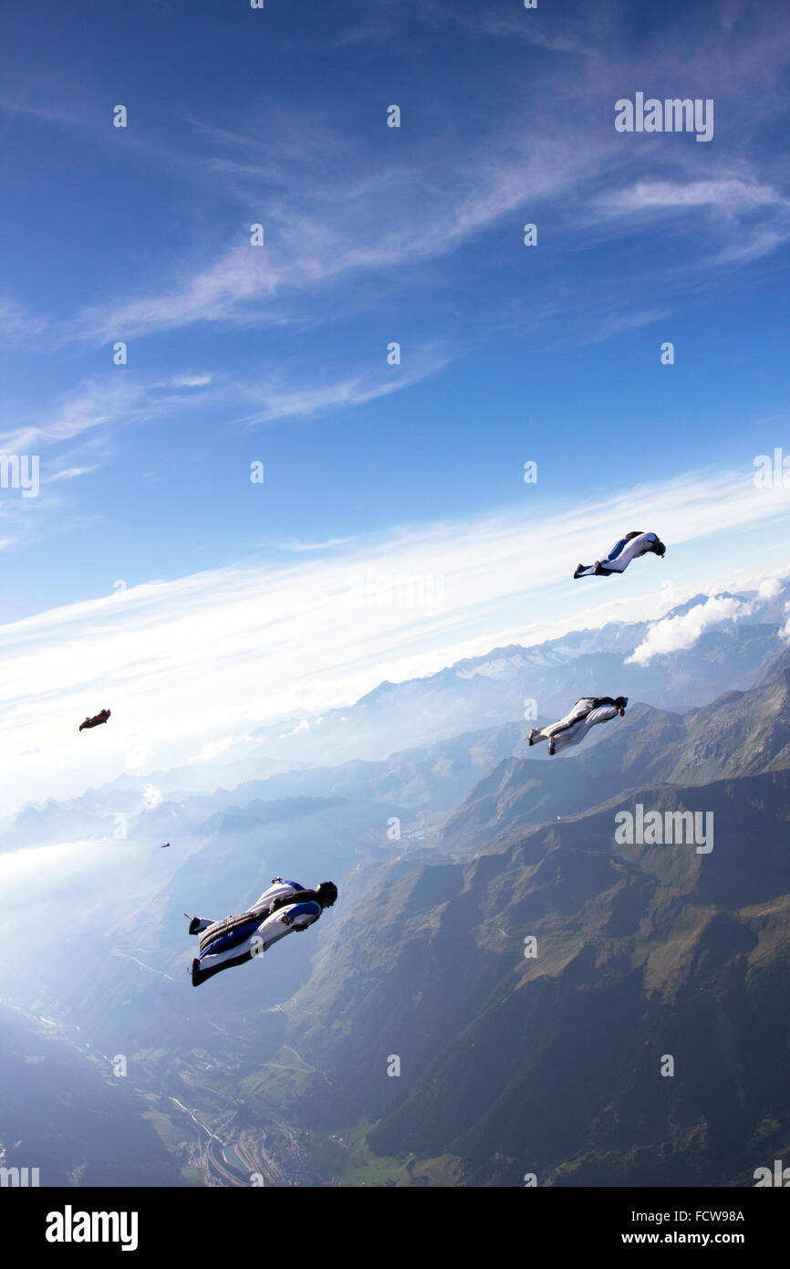 Wingsuit pilots are flying in a group together. The leader in the white ...