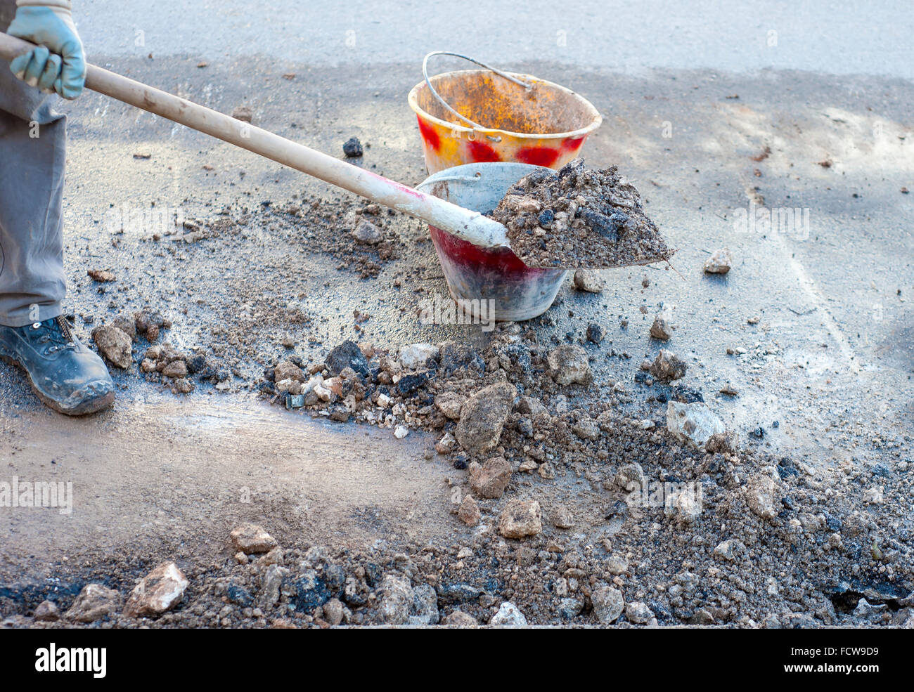 cleaning rubble from the road, worker works with a shovel and bucket ...