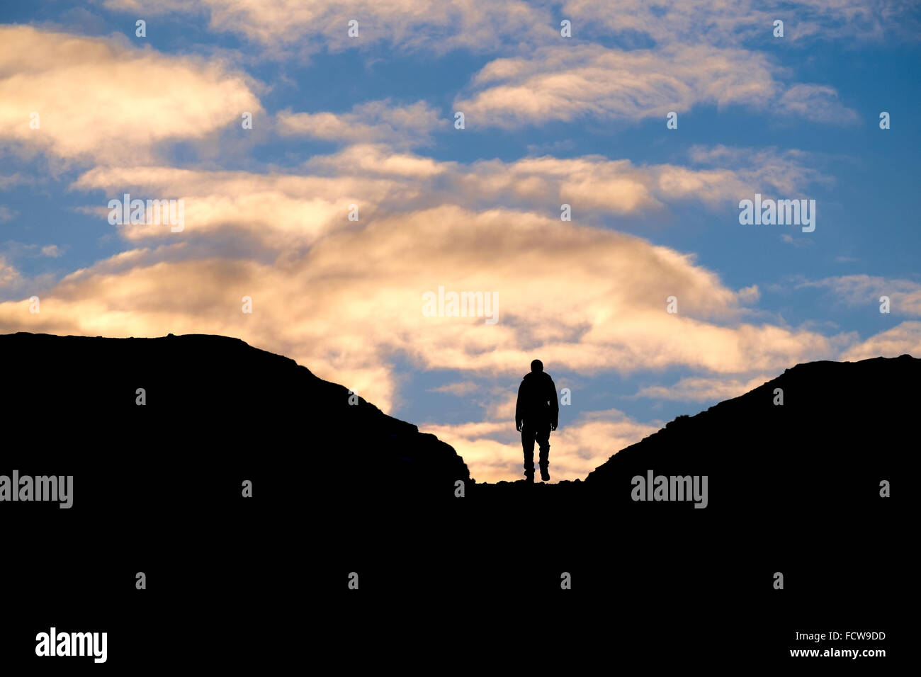 A walker passing through Heaven's Gate on the Wrekin hill at sunset ...