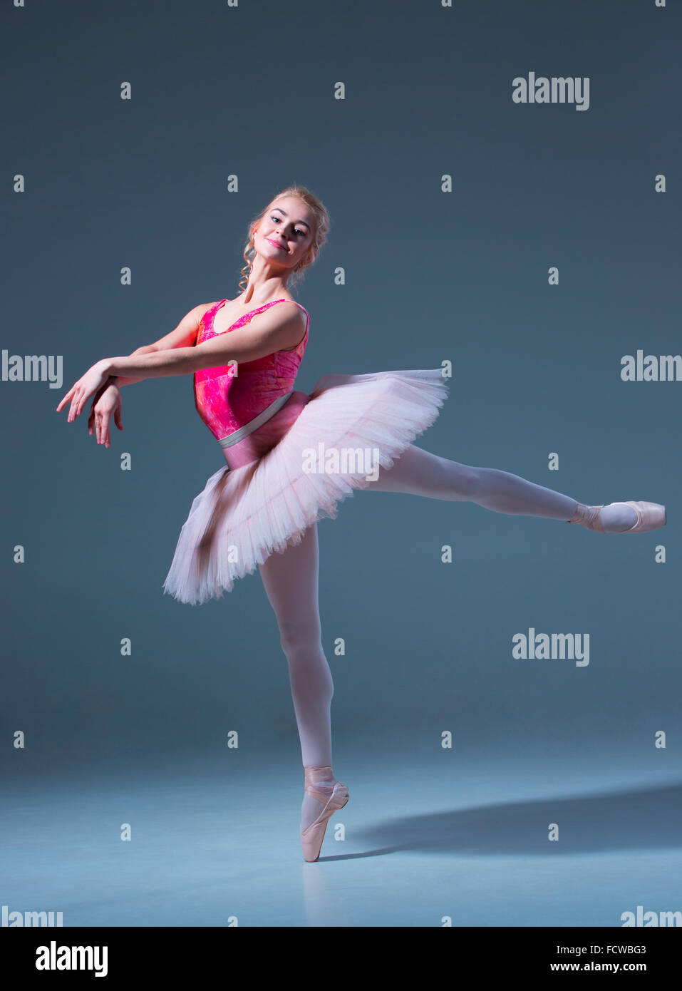 Portrait of the ballerina in ballet pose on a grey background ...