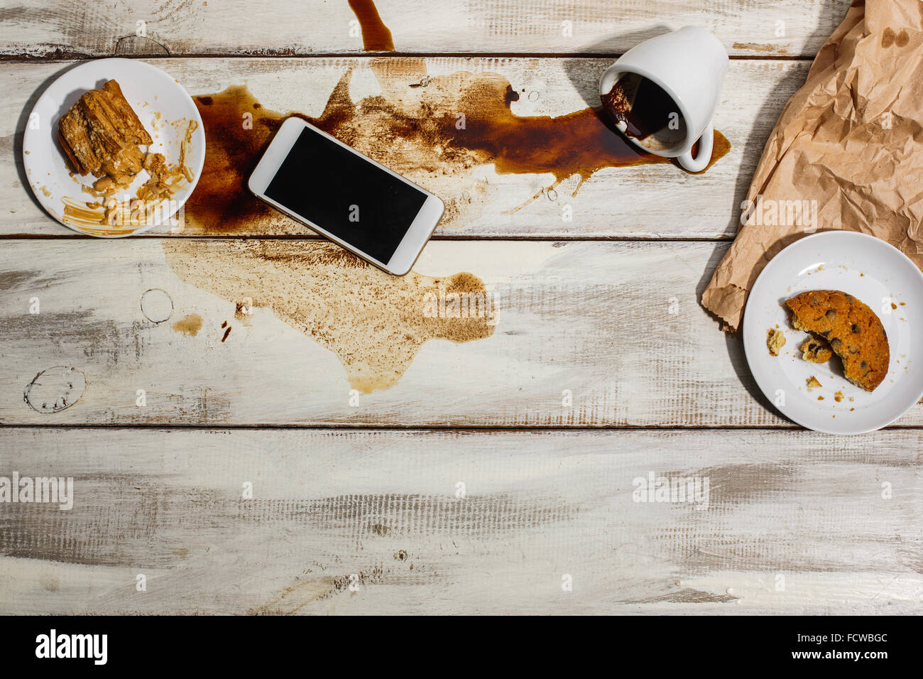 Cup of coffee spilled on wooden table with the phone and and the ...