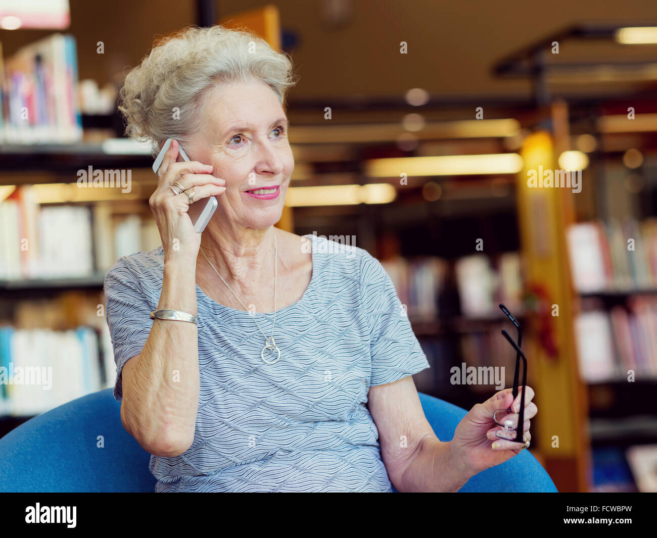 Elderly lady with mobile phone in library Stock Photo - Alamy