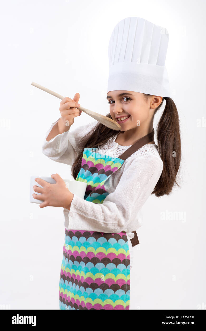 Laughing pretty little cook in a chefs toque and colorful apron ...