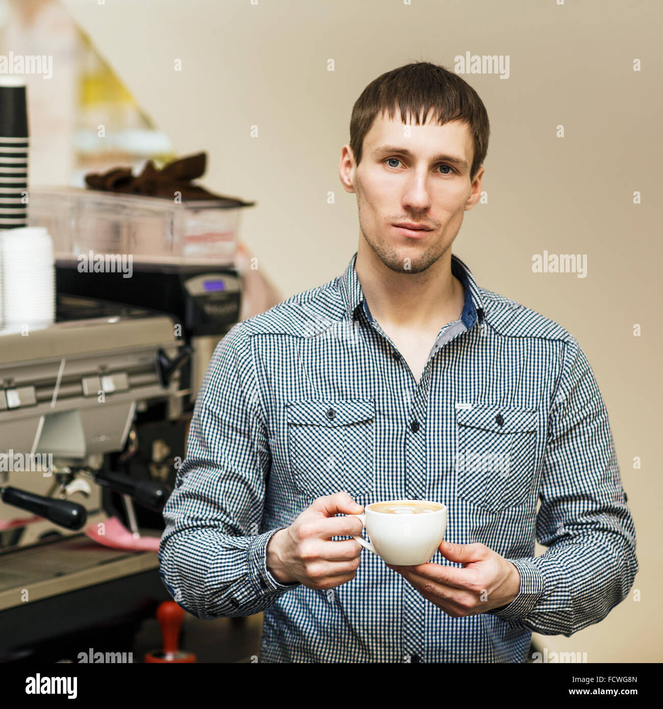 Young barista standing with crossed arms with coffee maker on ...