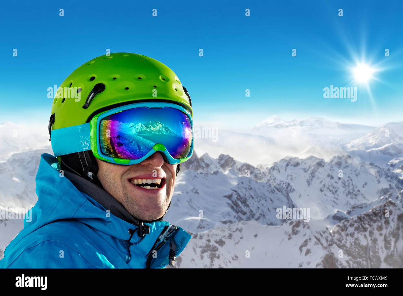 Portrait of happy young skier during sunny day. Panorama of Alps on ...