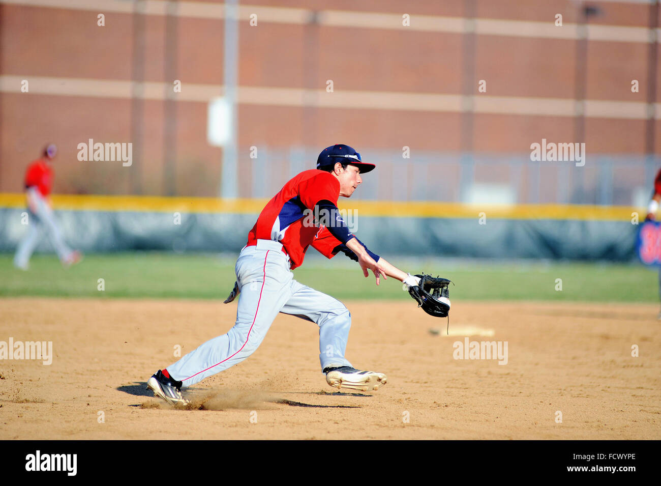 A charging shortstop gloveing a ground ball before throwing on to first ...