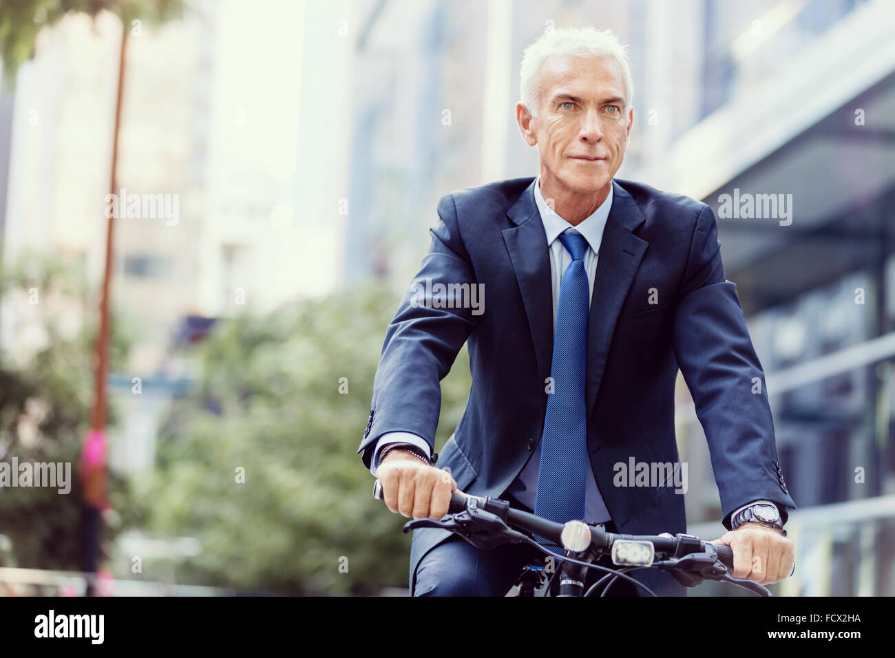 Successful businessman in suit riding bicycle Stock Photo - Alamy
