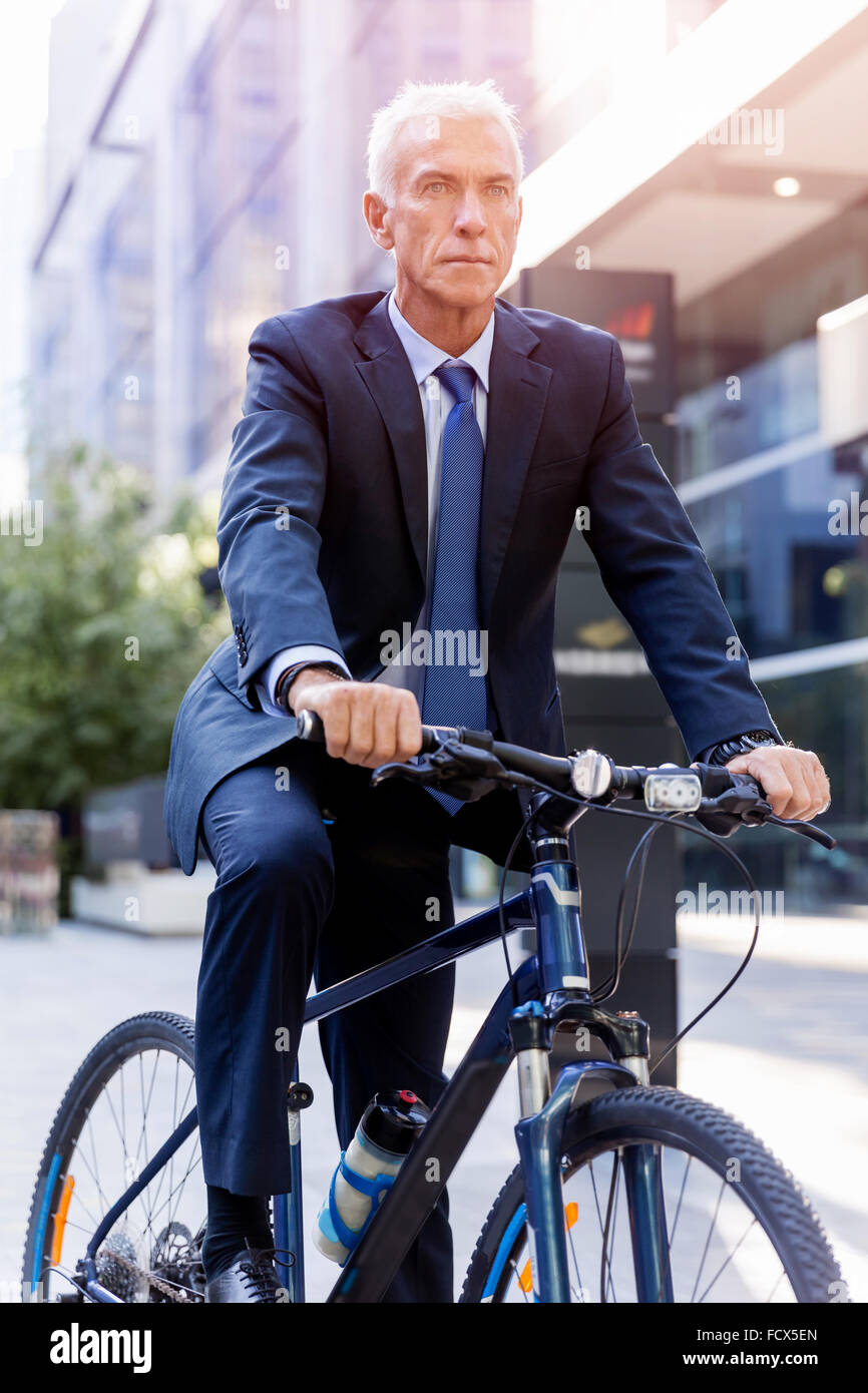 Successful businessman in suit riding bicycle Stock Photo - Alamy
