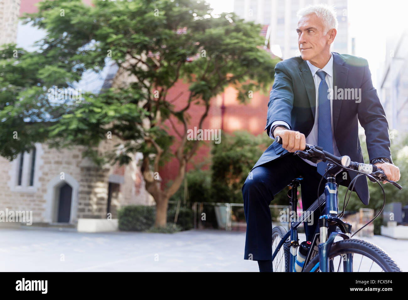 Successful businessman in suit riding bicycle Stock Photo - Alamy