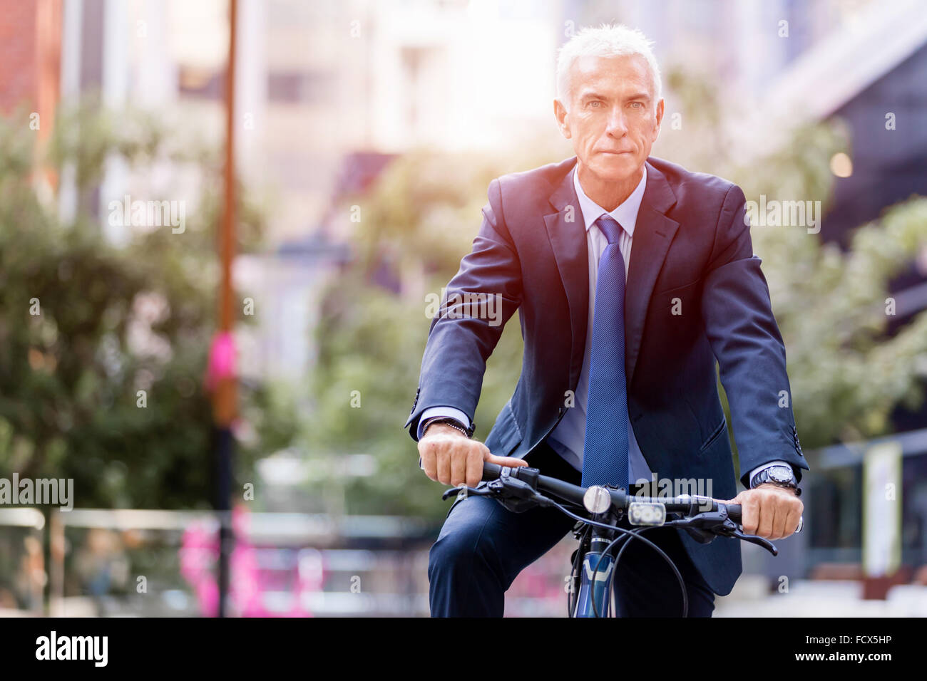 Successful businessman in suit riding bicycle Stock Photo - Alamy