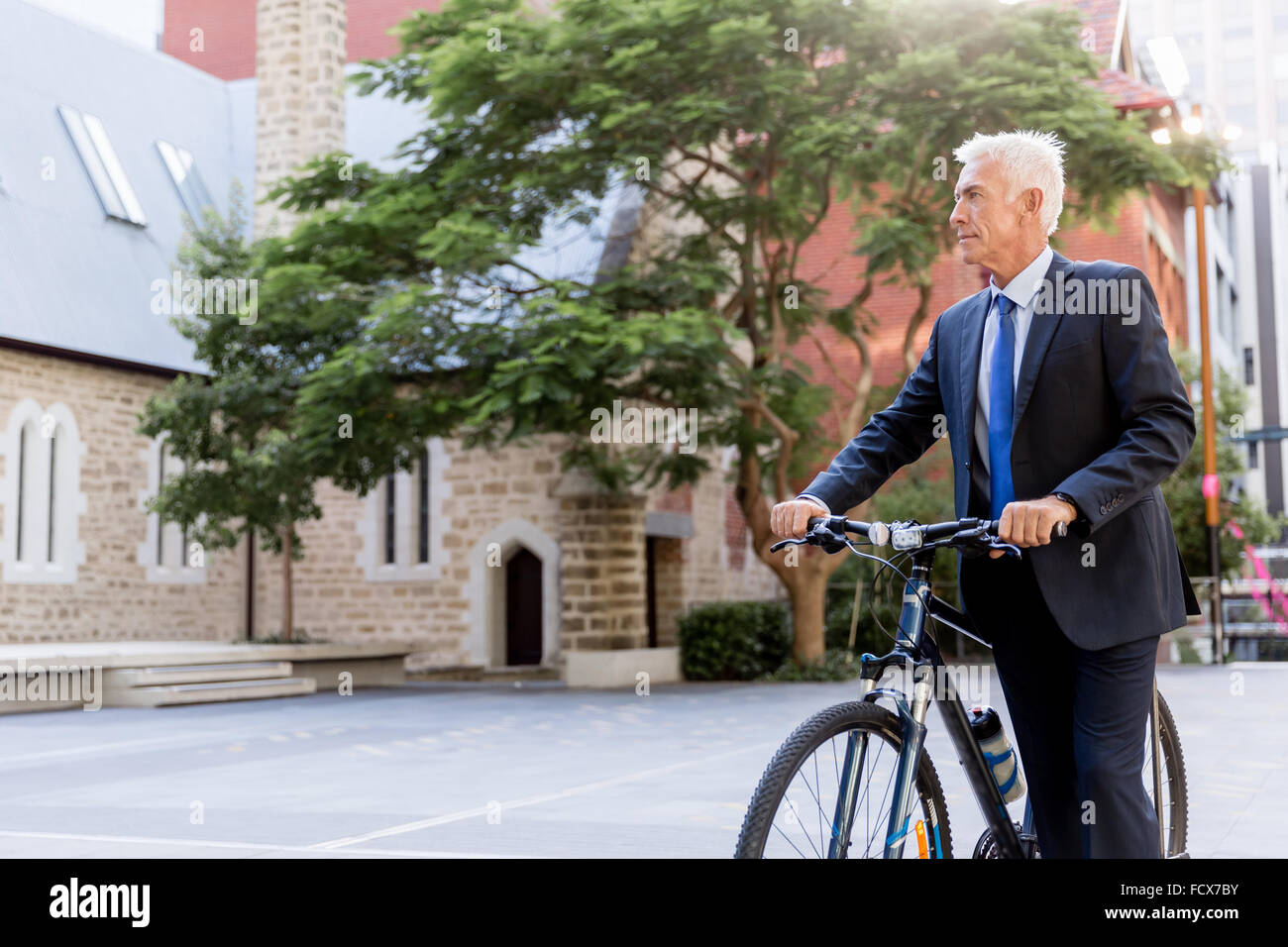 Successful businessman in suit riding bicycle Stock Photo - Alamy