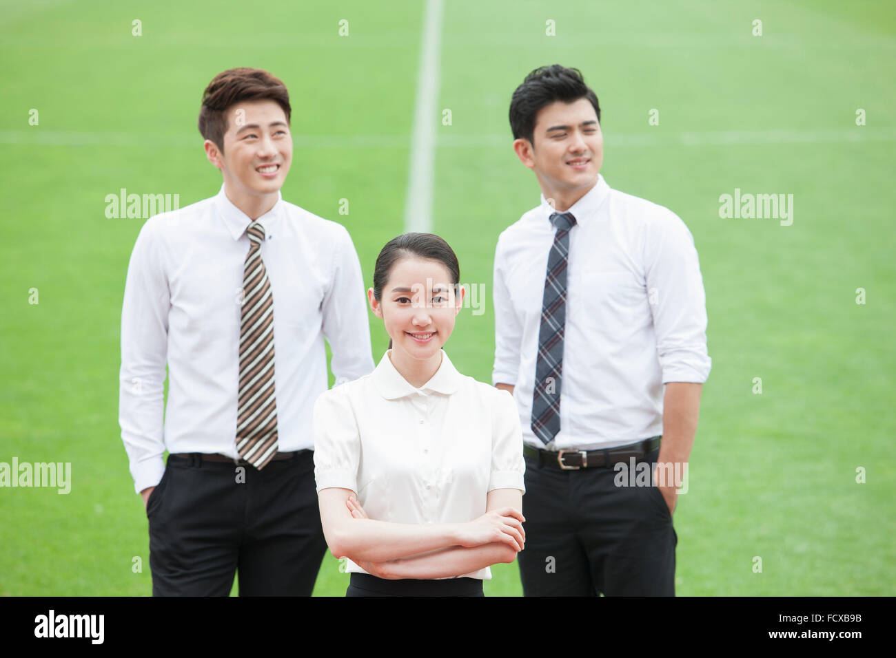 Two business men and woman staring forward with the background of grass ...