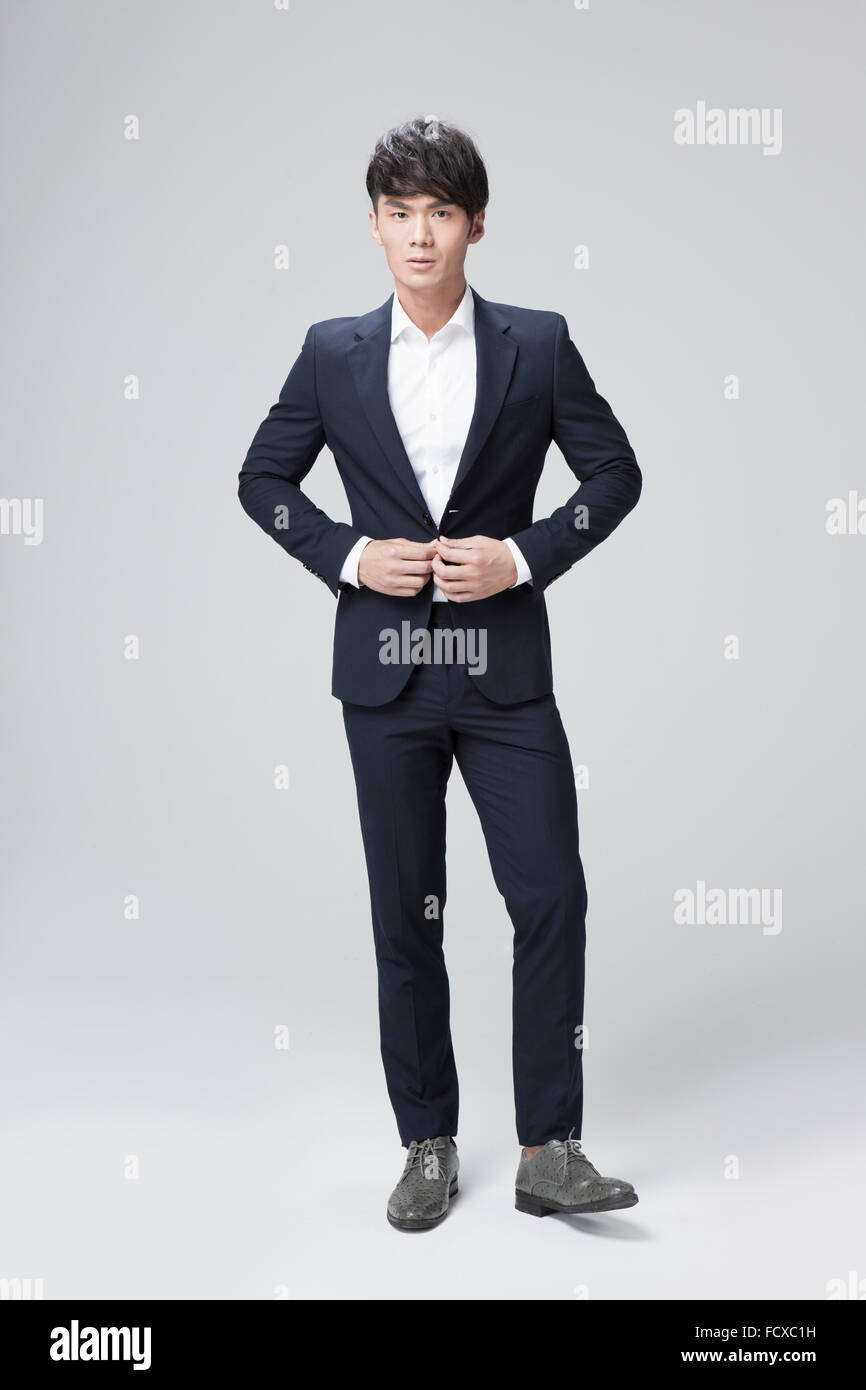 Man in black suit standing and staring forward with his hands on his ...