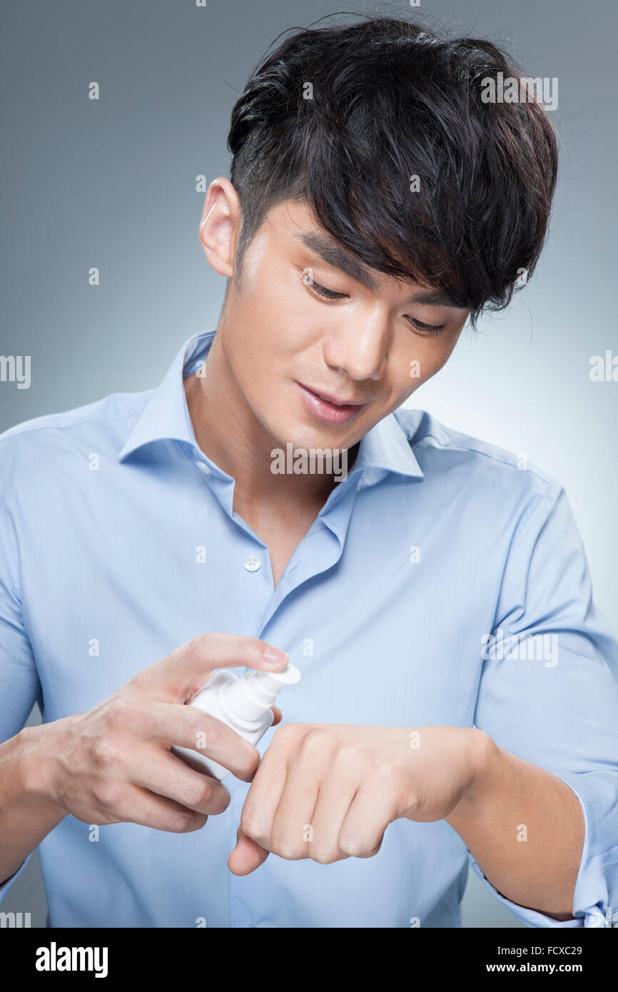 Man in blue shirt pumping a lotion on the back of his hand and looking ...