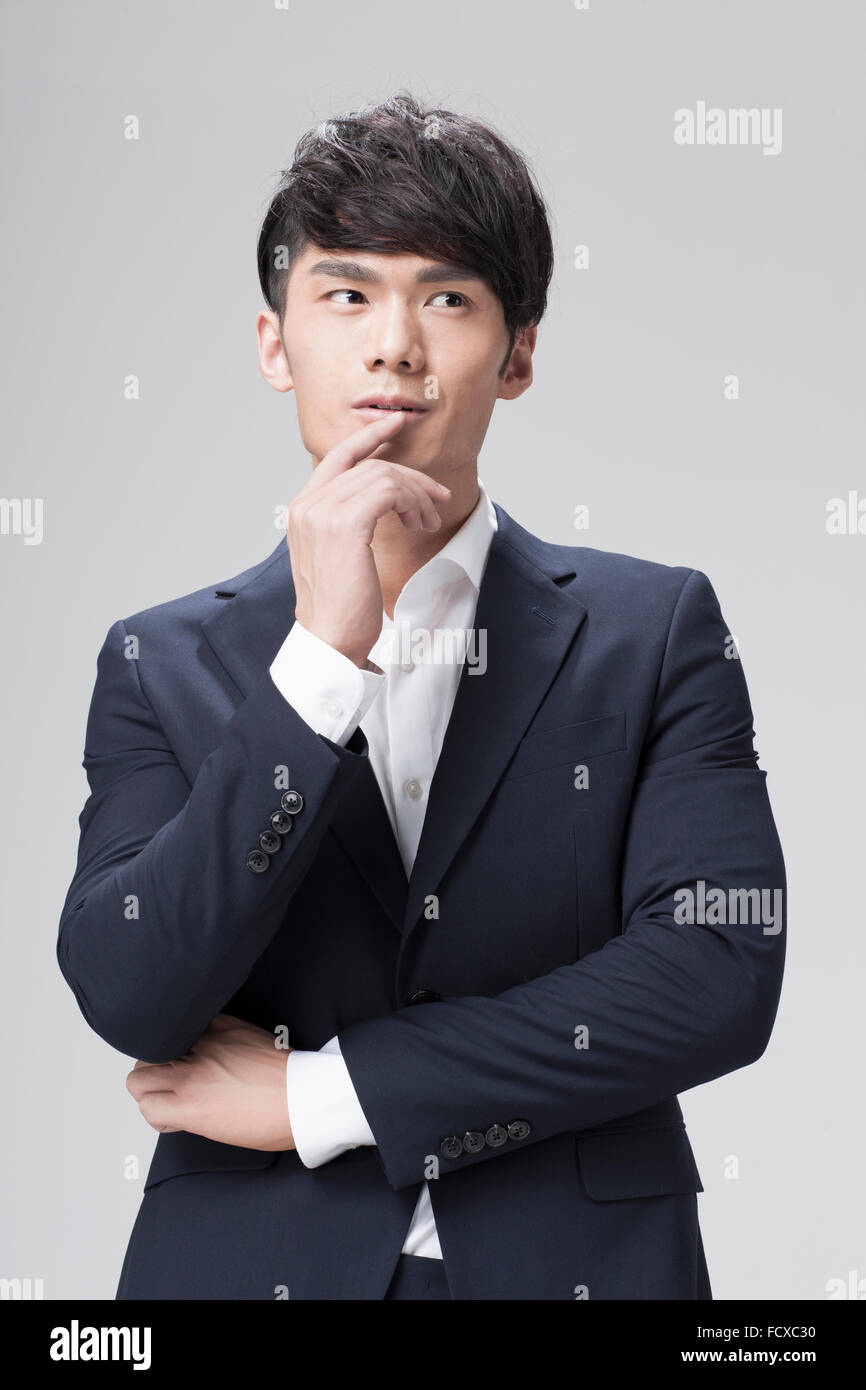 Man in black suit staring upward with the gesture of thinking with his ...