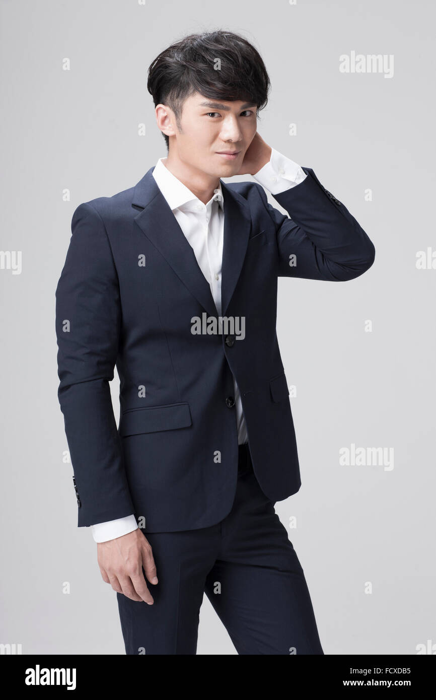 Man in black suit putting his hand behind his neck and staring forward ...