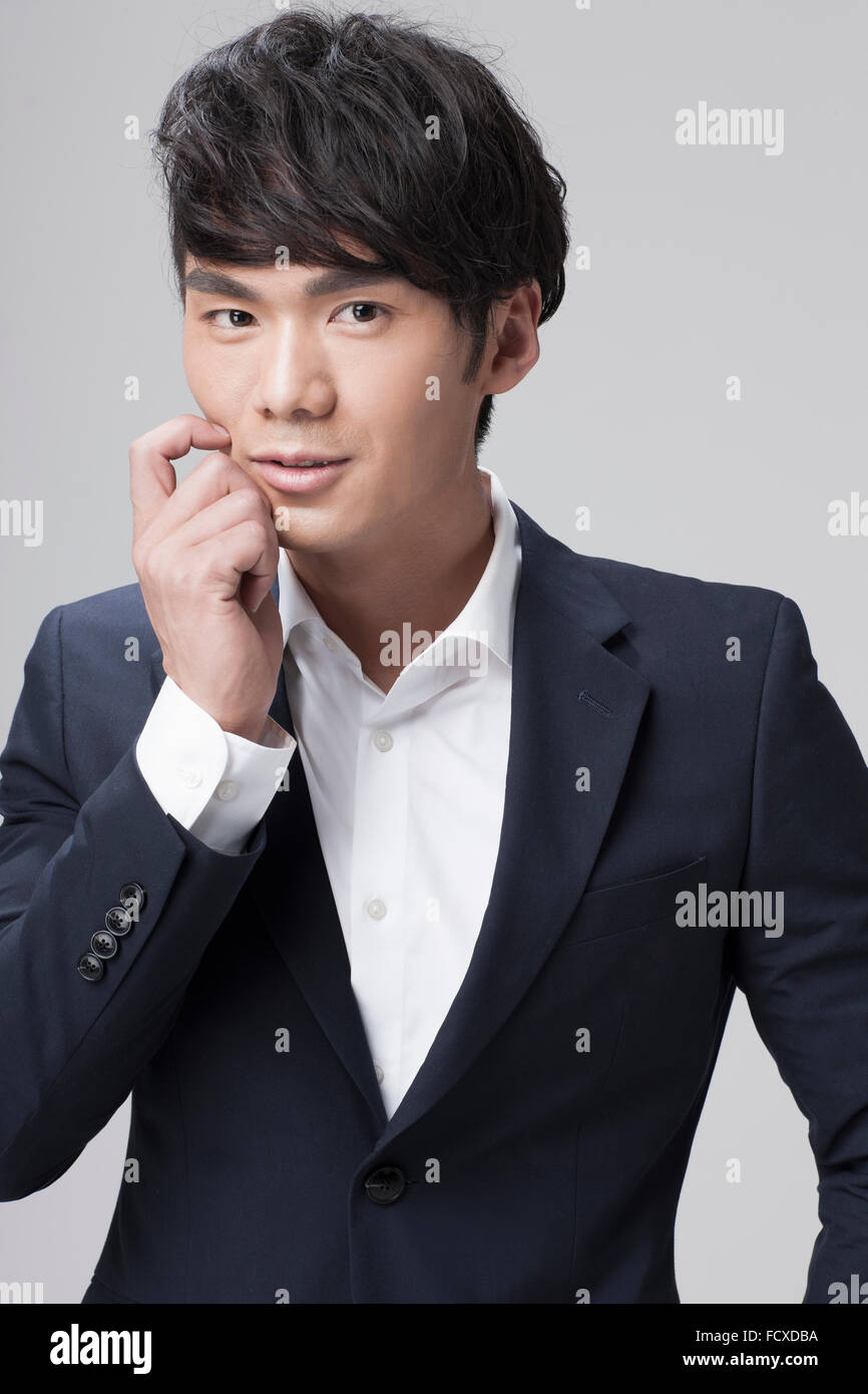 Man in black suit staring forward with his hand on his face and smiling ...