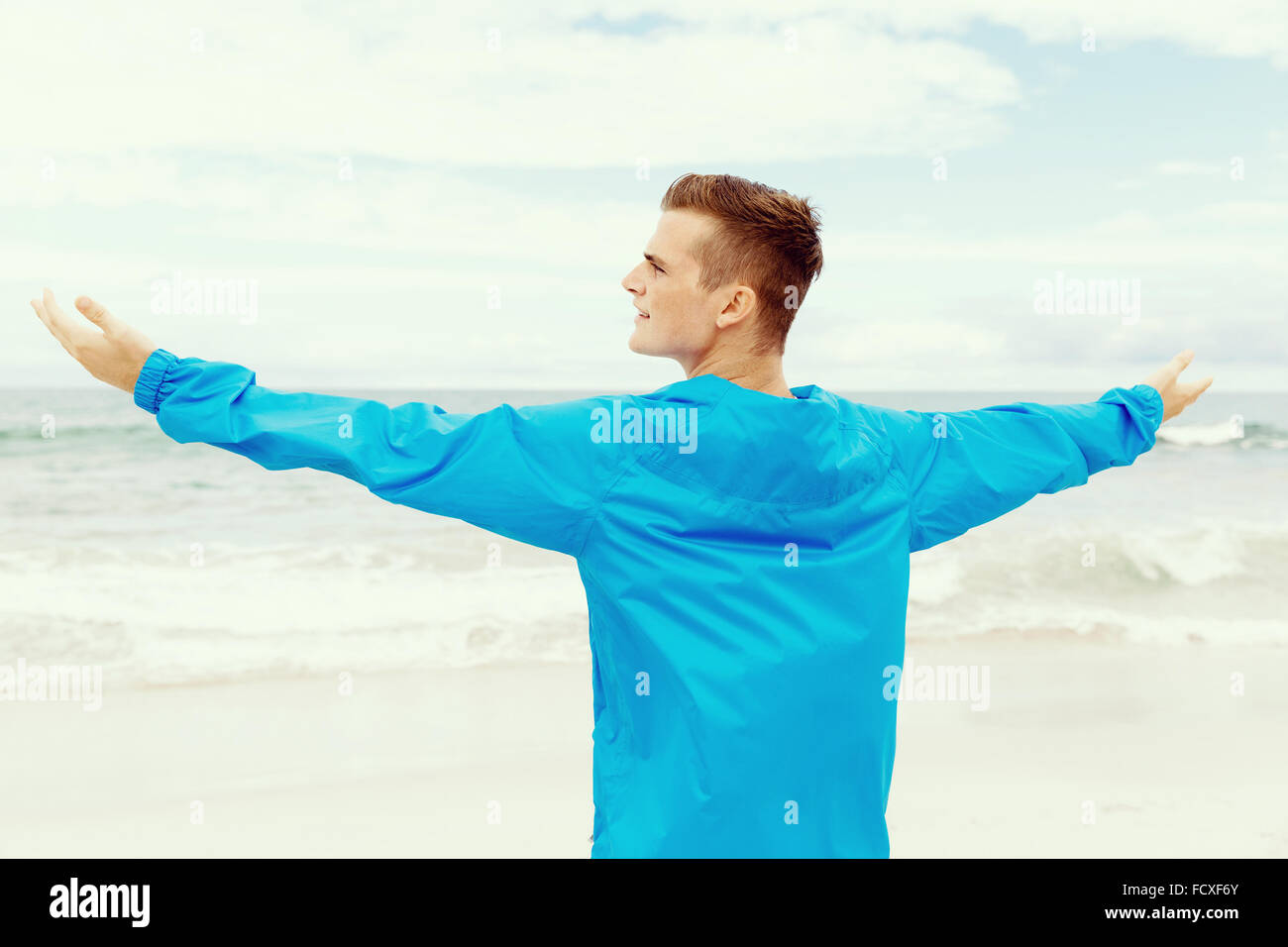 Young man in sport wear with outstretched arms standing on beach Stock ...