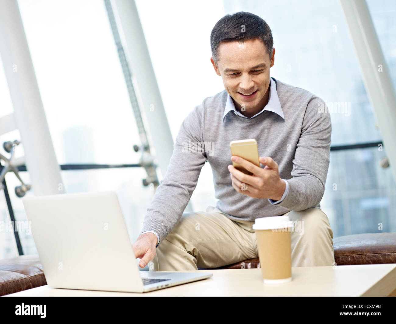 man using mobile phone and laptop computer in office Stock Photo - Alamy