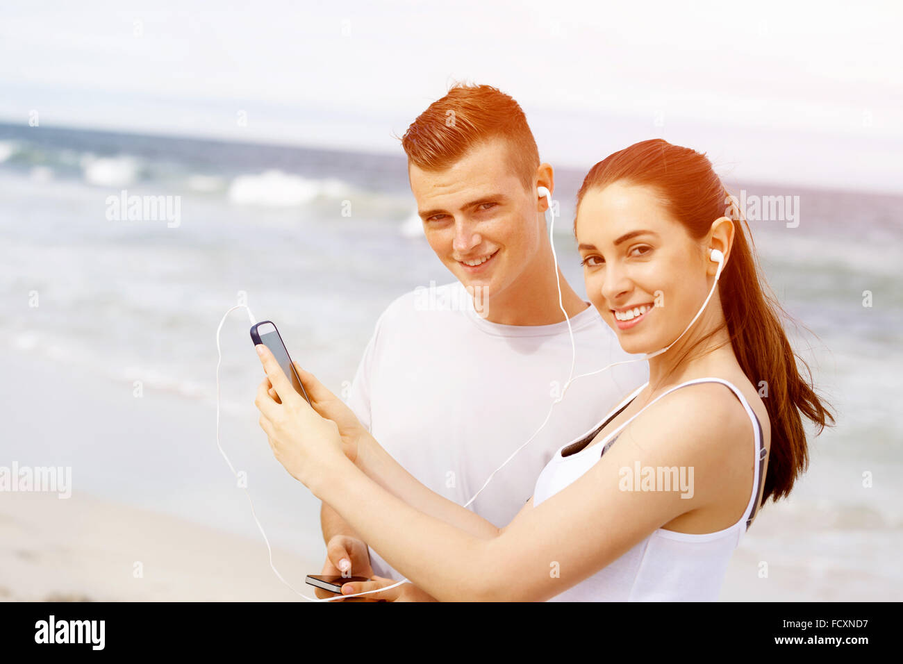 Young couple of runners with mobile smart phone outdoors on beach Stock ...