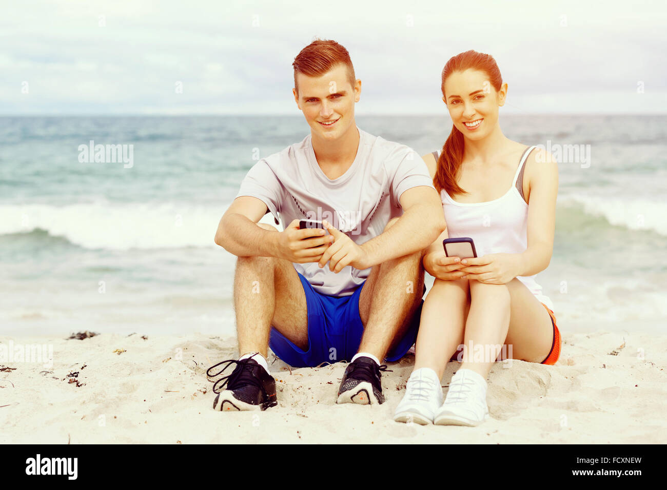 Young couple of runners with mobile smart phone outdoors on beach Stock ...