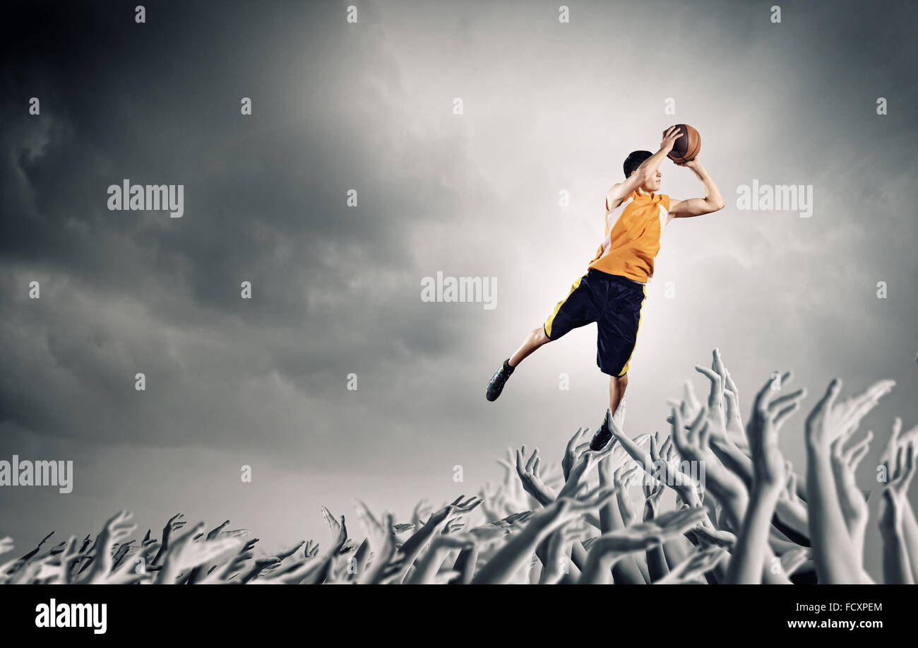 Young man throwing ball into basket in jump Stock Photo - Alamy