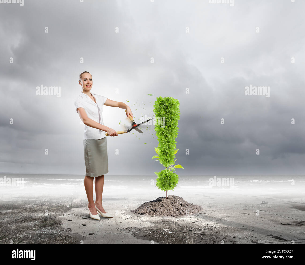 Young attractive businesswoman cutting plant in shape of exclamation ...