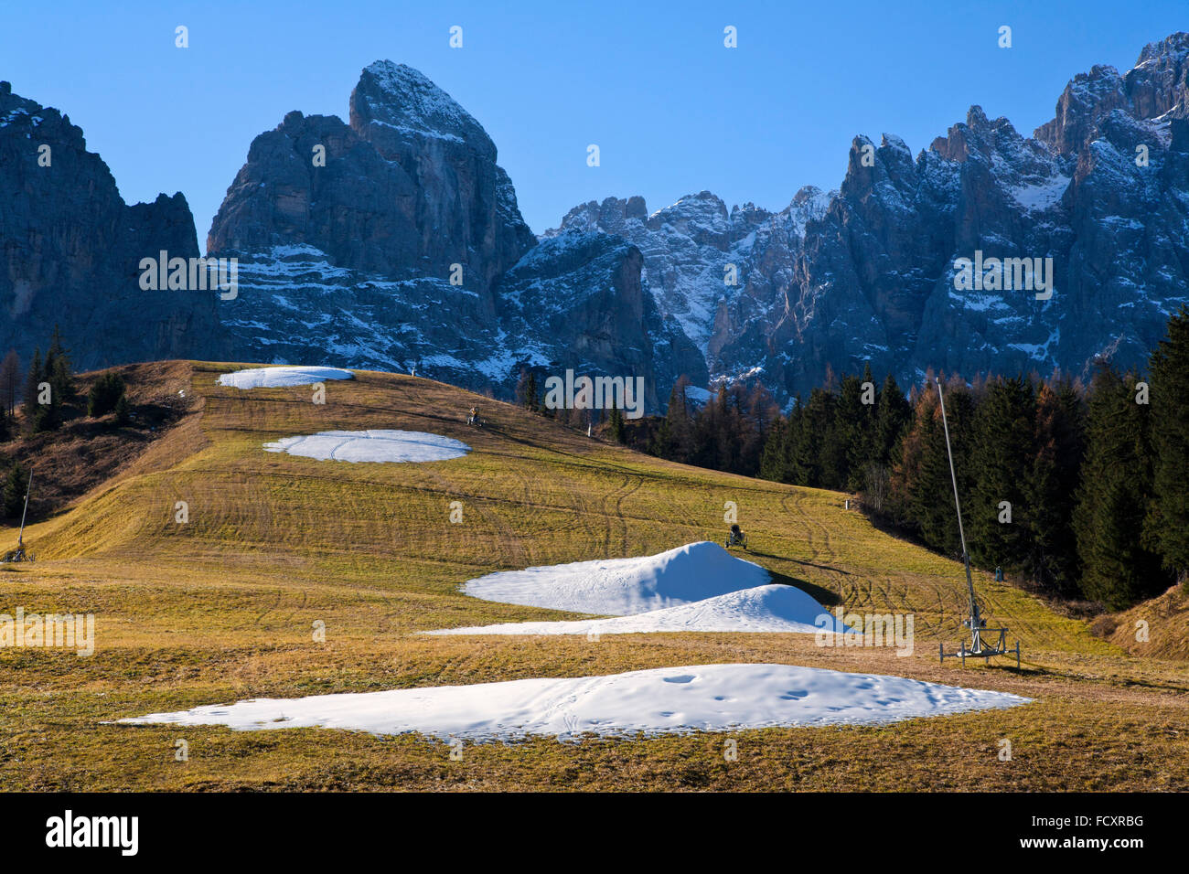 Snowmaking system in the fall, brown meadow with piles of snow, behind ...