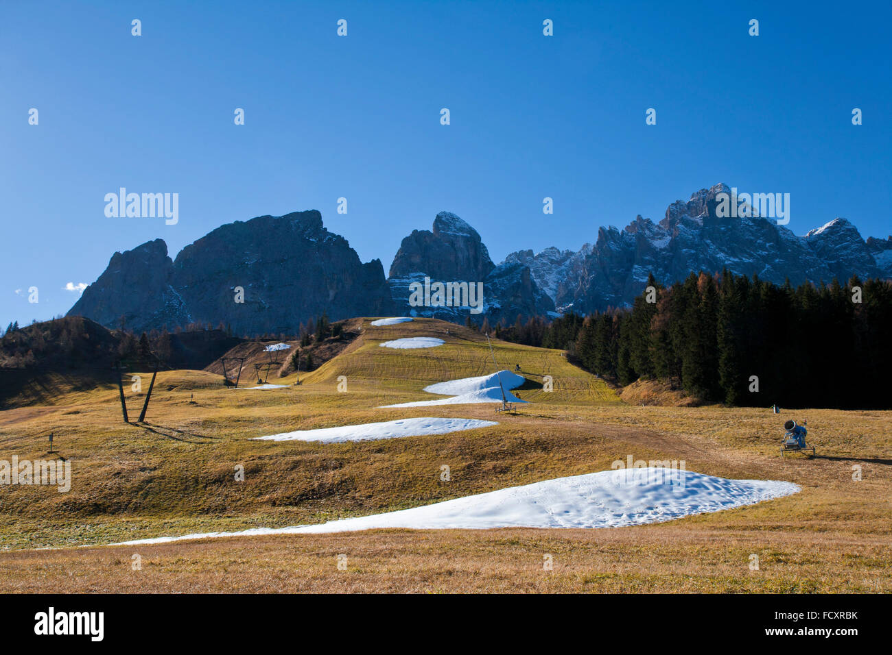 Snowmaking system in the fall, brown meadow with piles of snow, behind ...