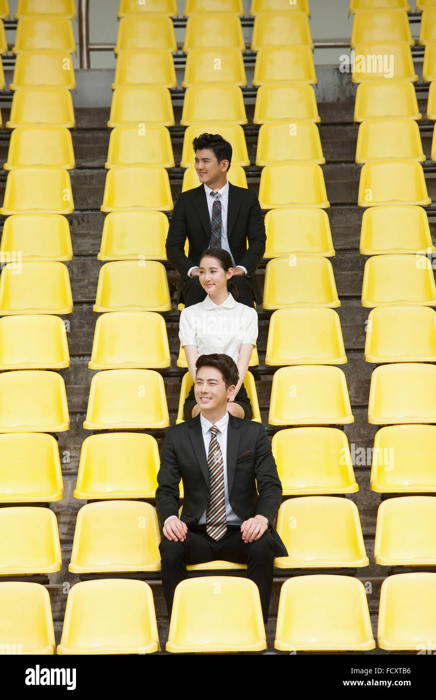 Three smiling business people sitting on stadium seats in a line Stock ...