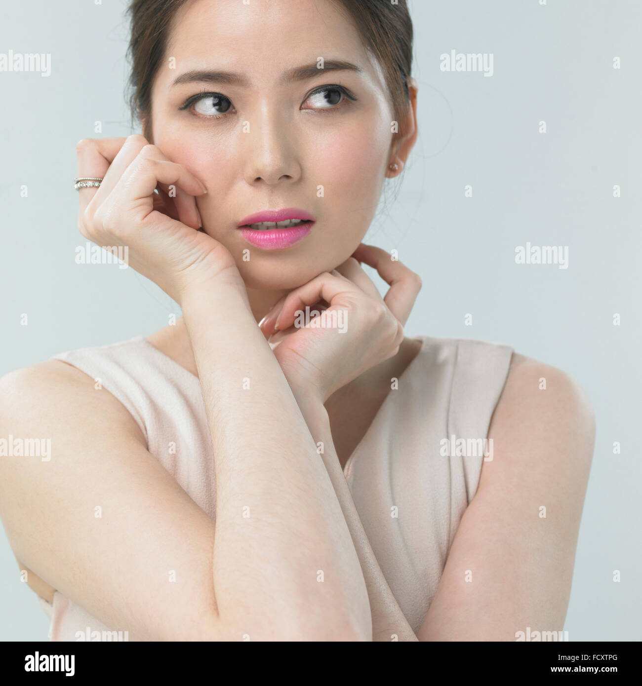 Portrait of young woman placing her face on her hands looking up Stock ...