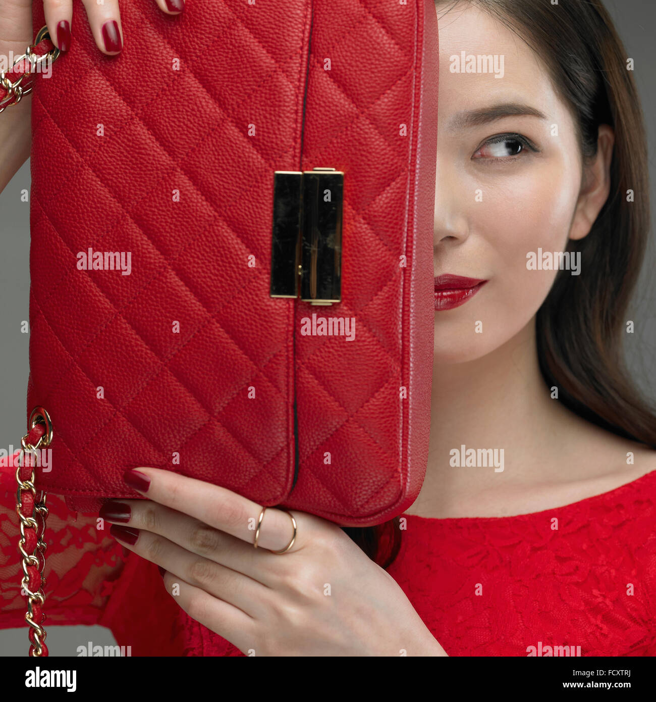 Portrait of young woman covering half face with a red bag Stock Photo ...