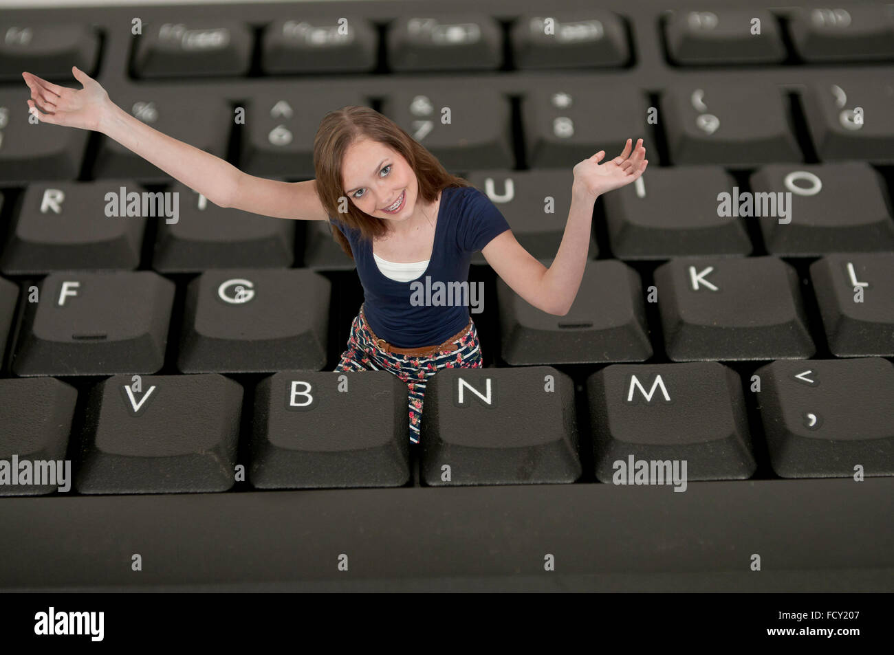 A beautiful computer savvy young teenage woman popping out of a laptop ...