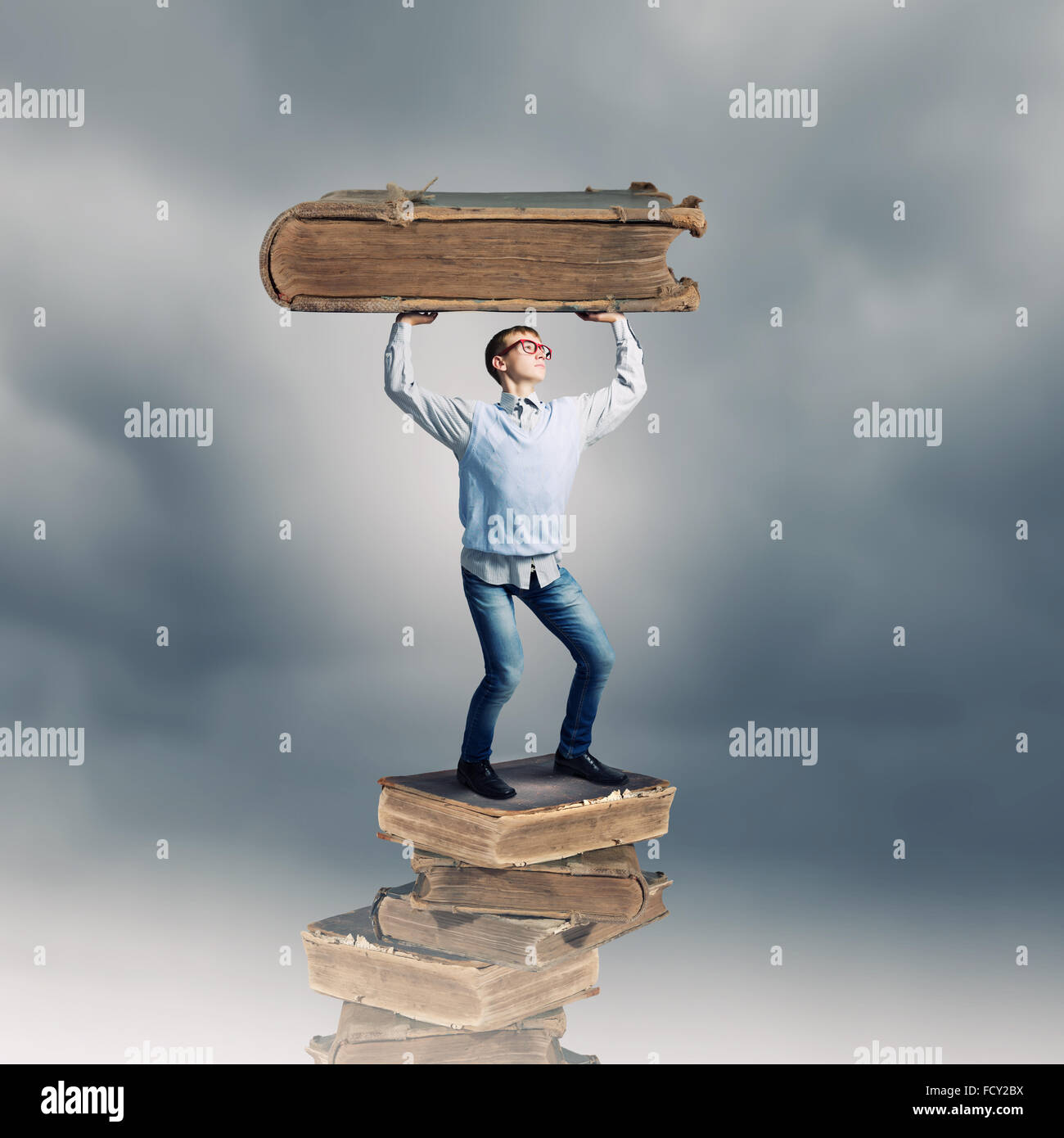 Young man holding huge book above head Stock Photo - Alamy