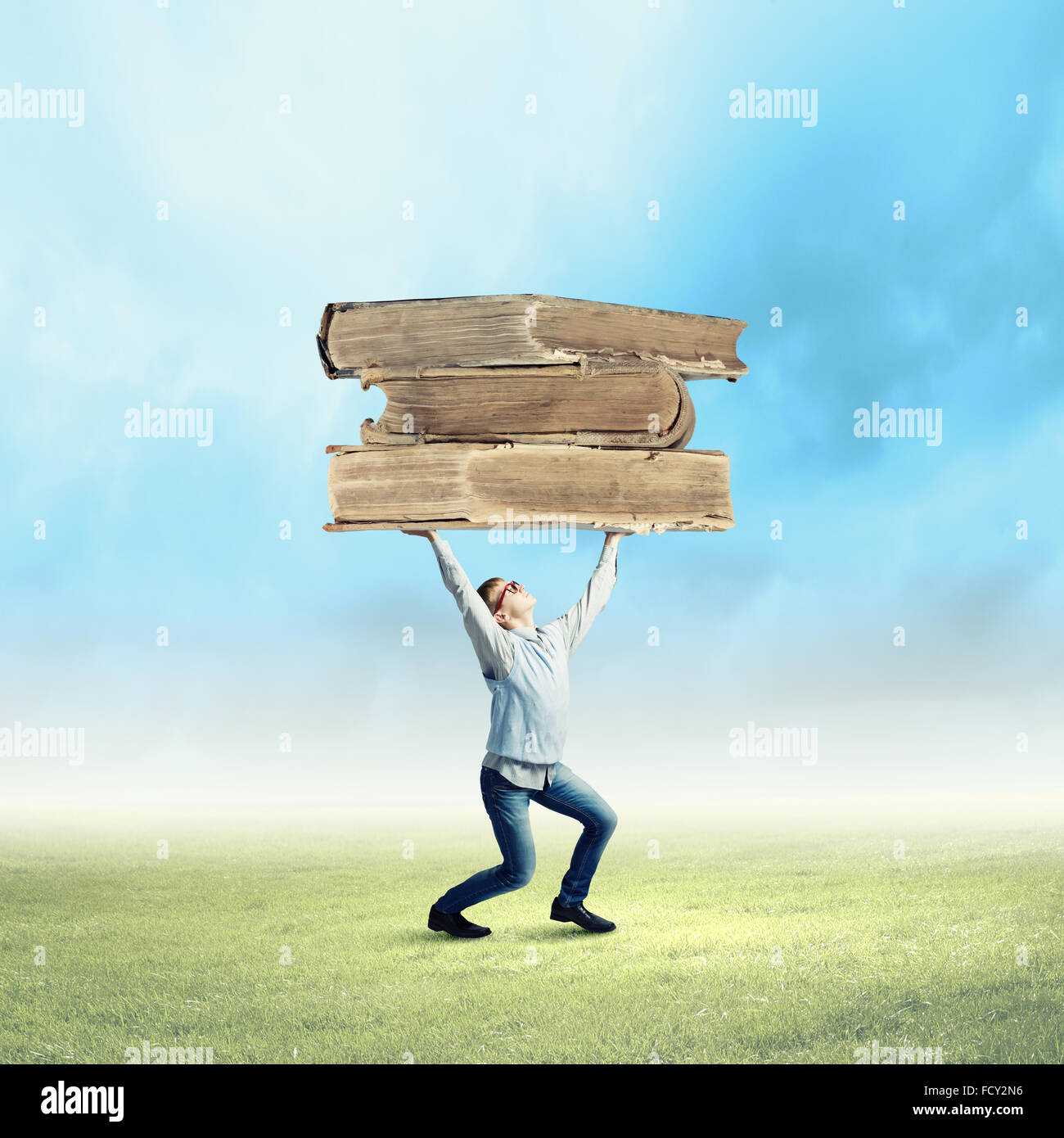 Young man holding huge book above head Stock Photo - Alamy