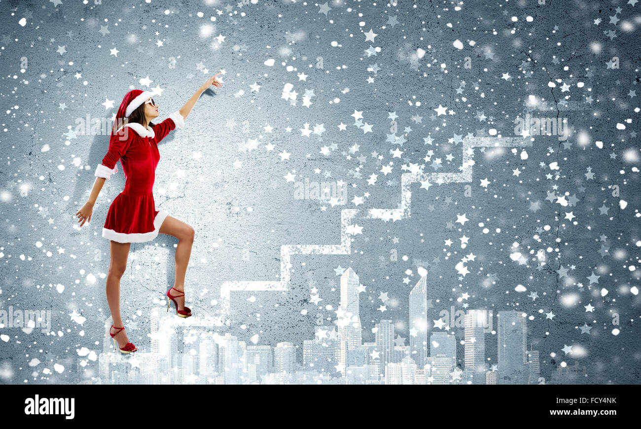 Attractive young woman in Santa suit walking on ladder Stock Photo - Alamy