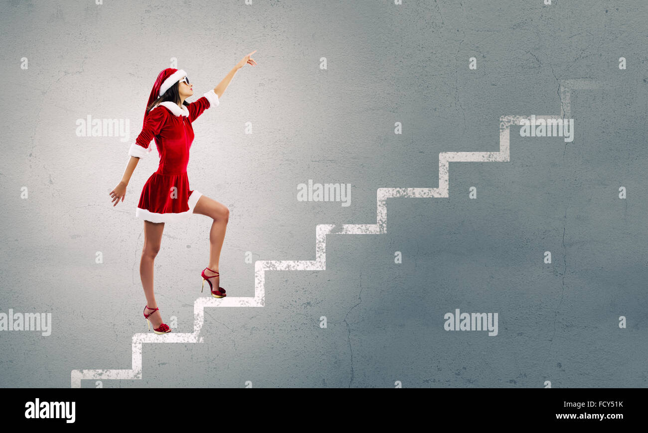 Attractive young woman in Santa suit walking on ladder Stock Photo - Alamy