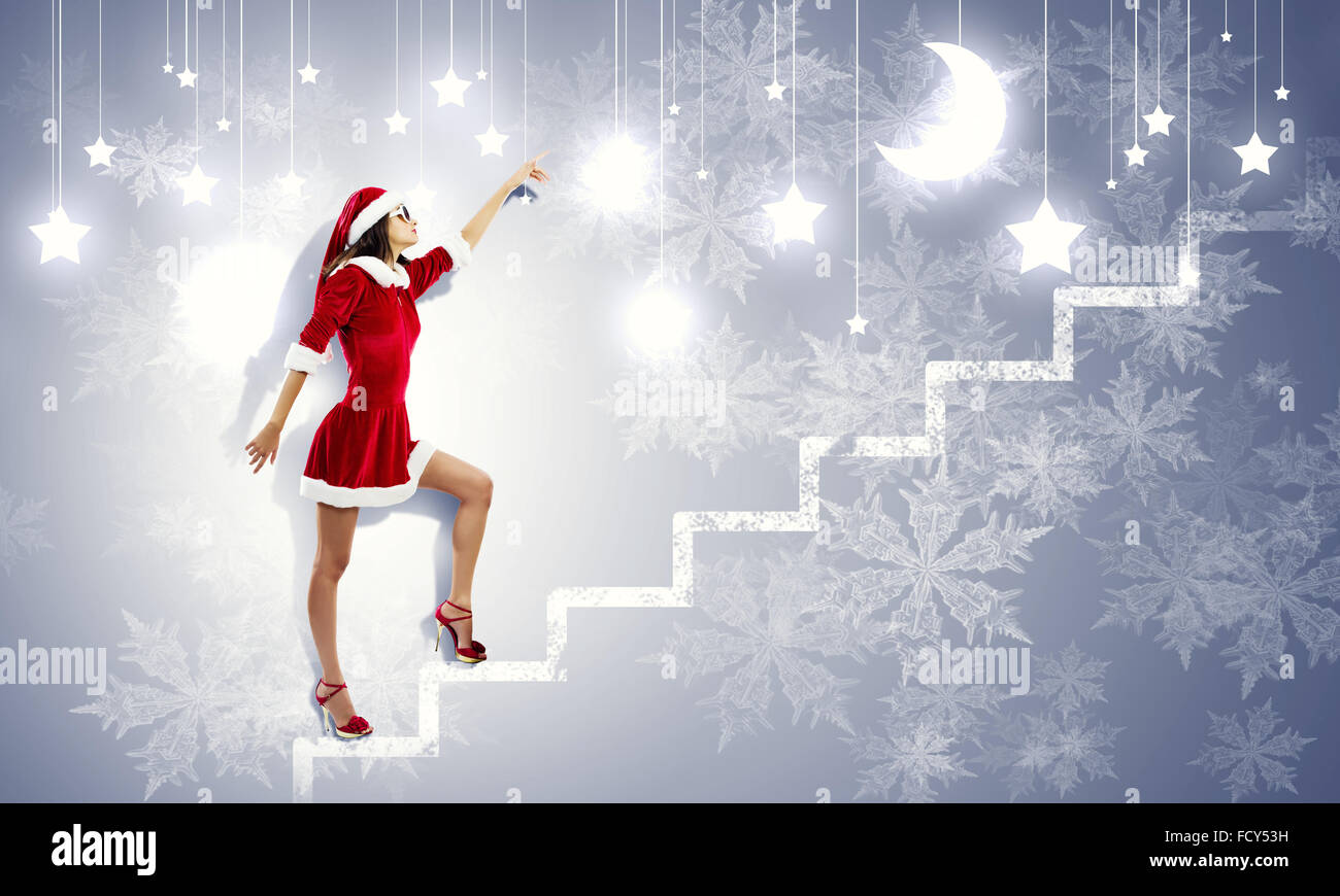 Attractive young woman in Santa suit walking on ladder Stock Photo - Alamy